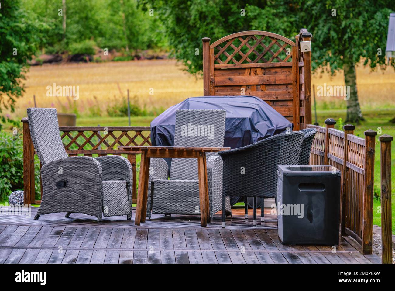 Heavy rain at wooden terrace with summer chairs, wooden table, grill ...