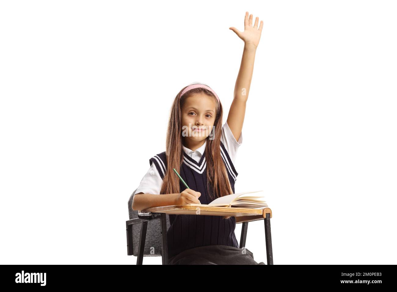 Schoolgirl in a uniform sitting on a chair and raising hand in class isolated on white ...