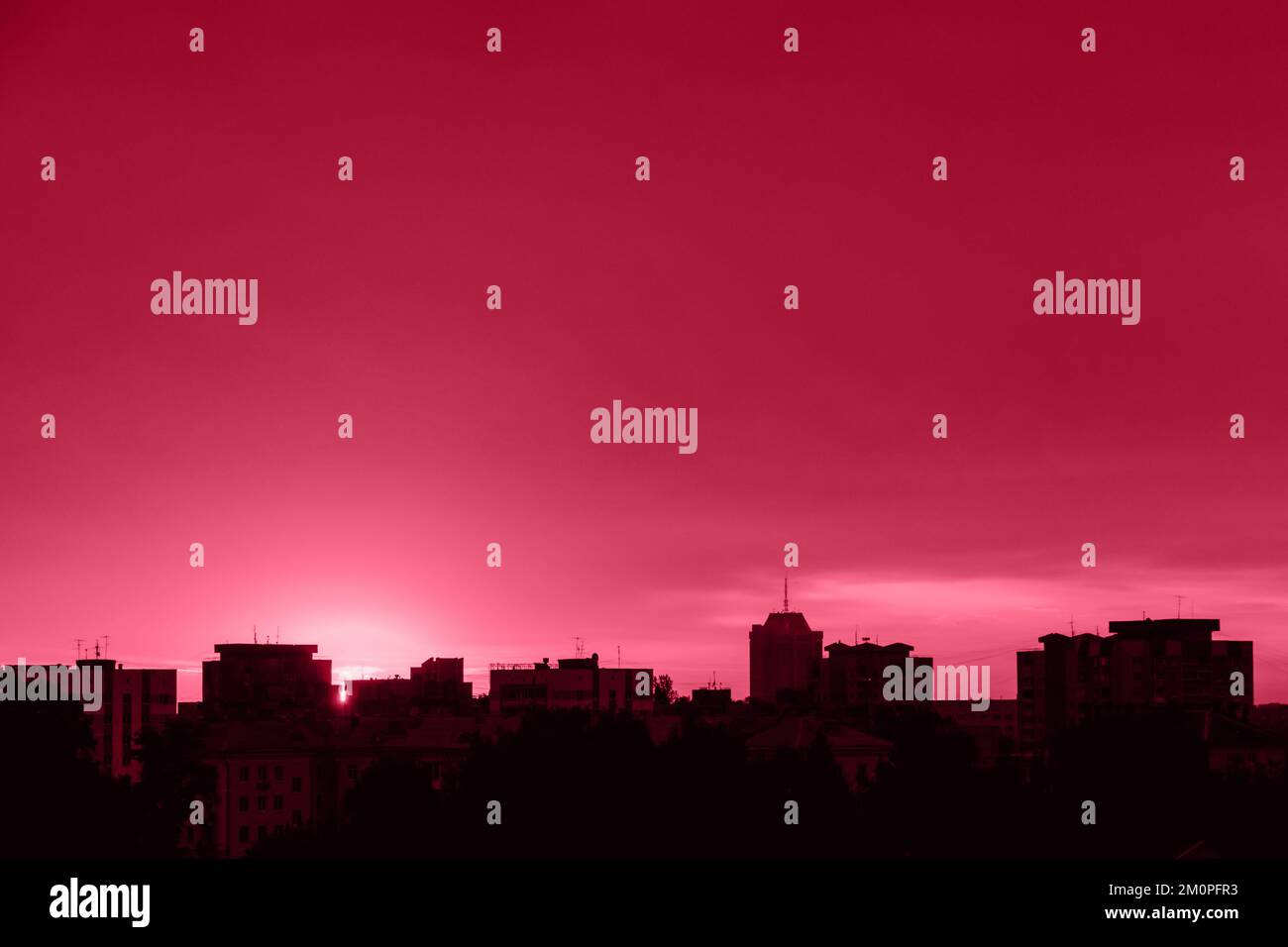 Silhouette of city at sunset. Sun is rising over tall buildings ...