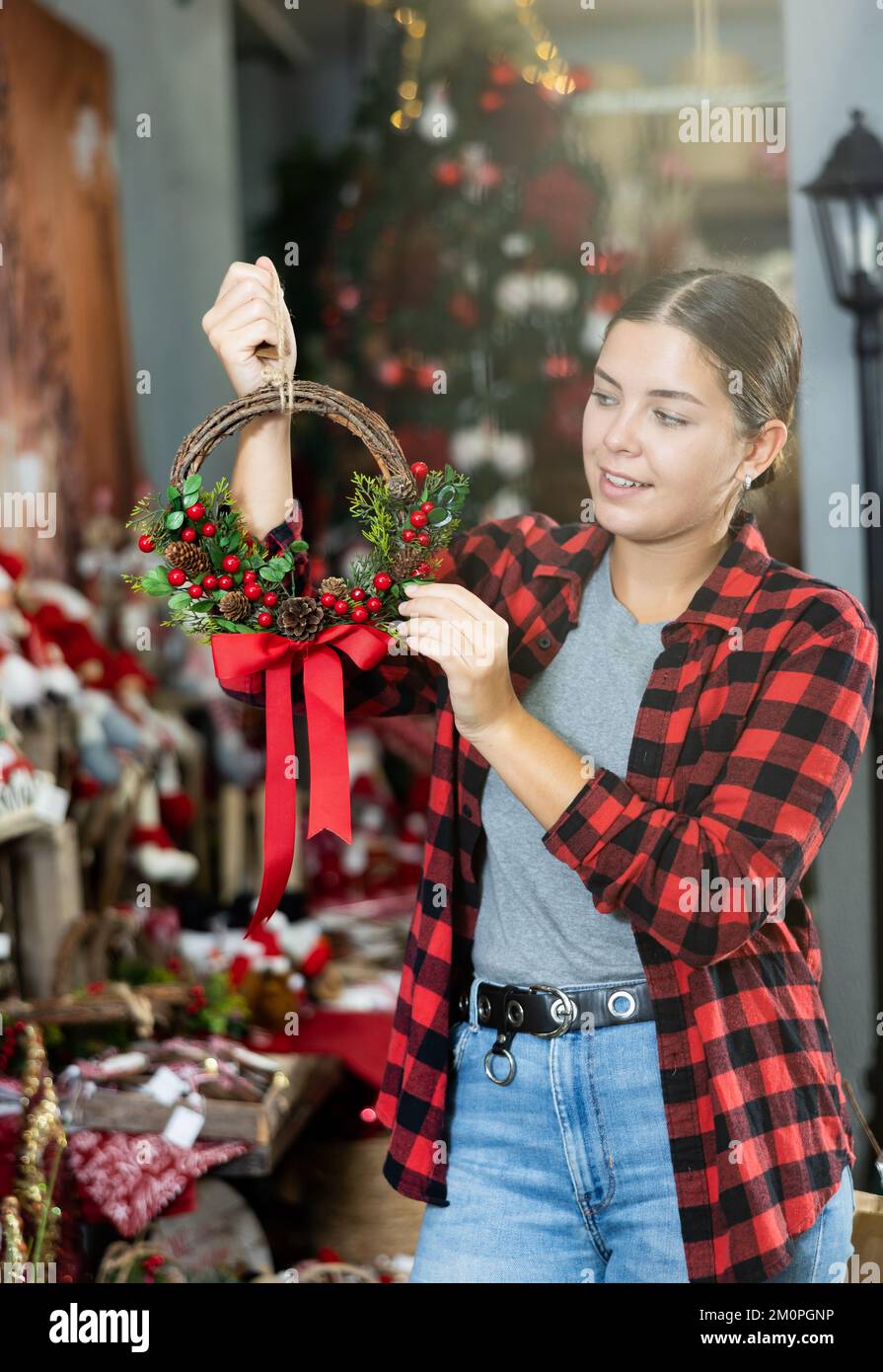 Happy female consumer choosing a farmhouse Christmas viburnum wreath at ...