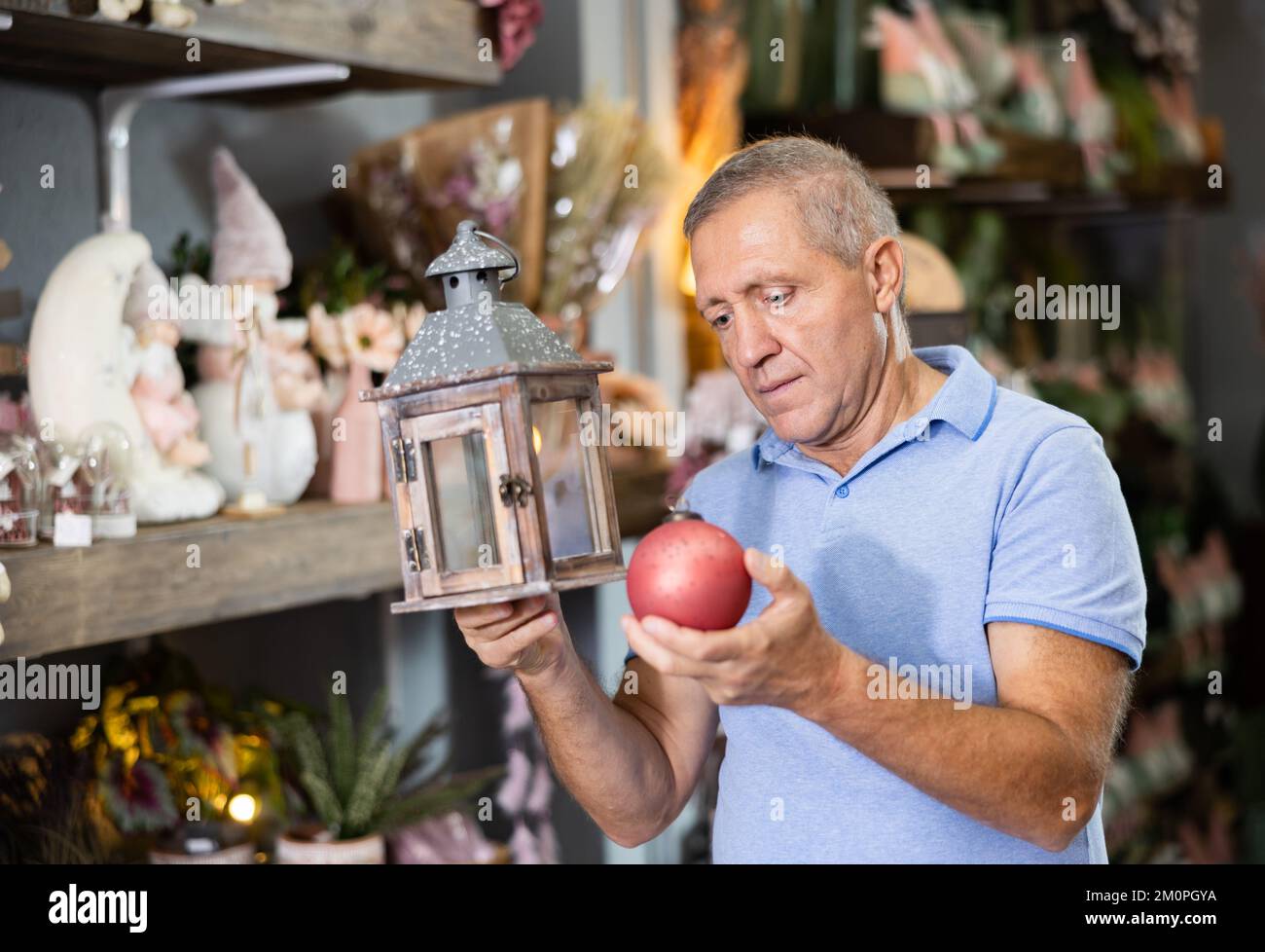 Middle-aged male consumer choosing Christmas decorations in a shopping ...