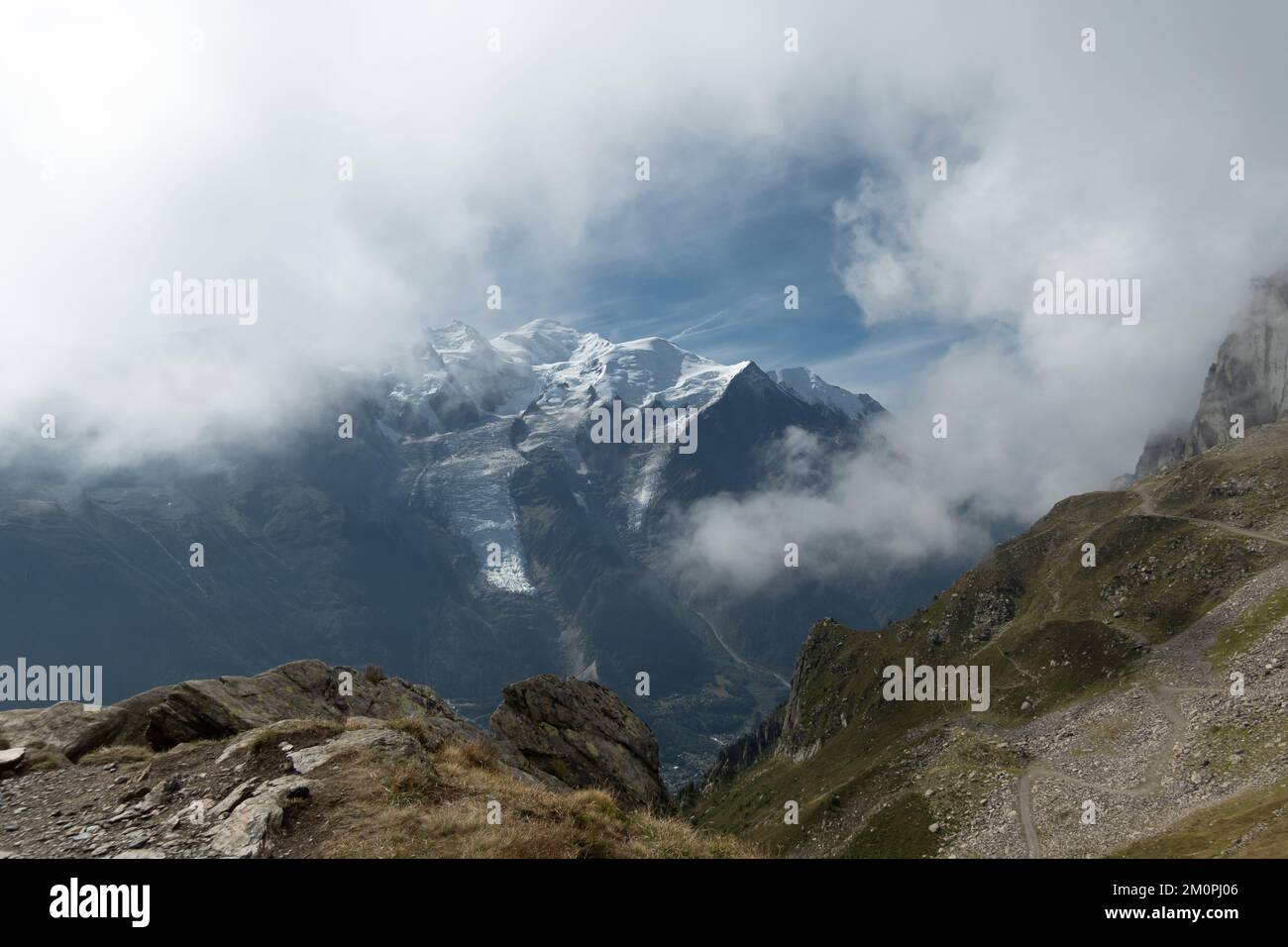 The Mont Blanc high mountain ridge visible through high clouds in summer in Chamonix in France ...