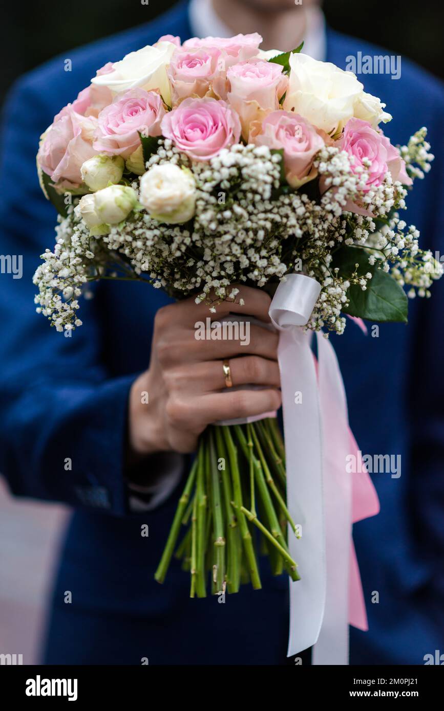 The bride in a white wedding dress is holding a bouquet of white ...