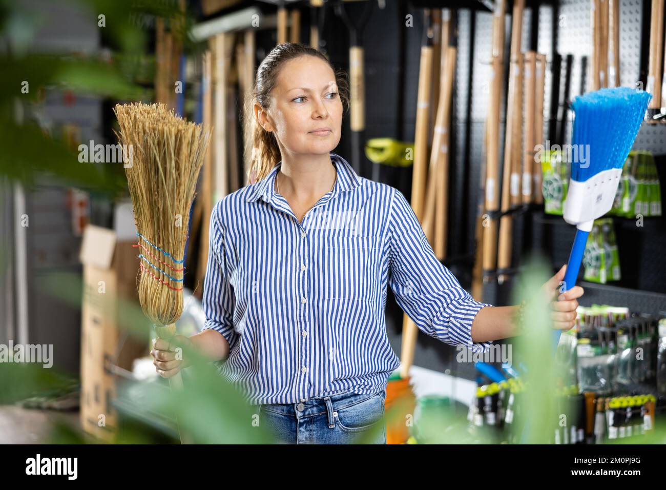 Woman choosing broom in household store Stock Photo - Alamy