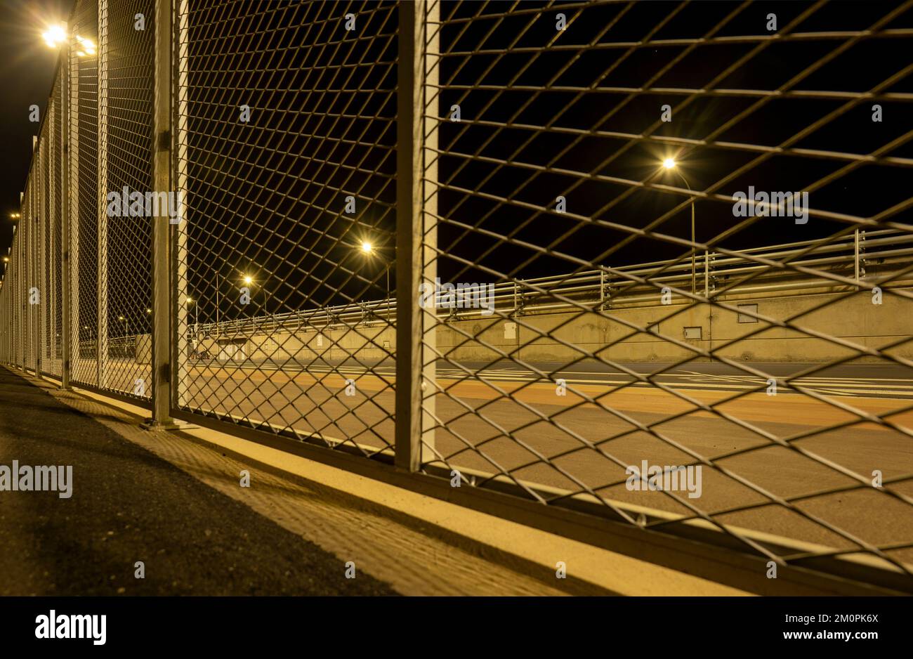 Metal fence with locked area at night Stock Photo - Alamy