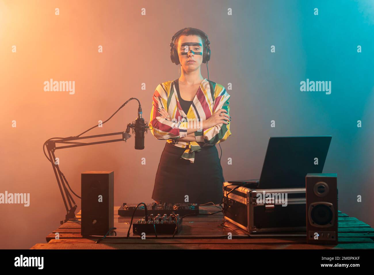 Female performer posing with arms crossed at turntables, using ...