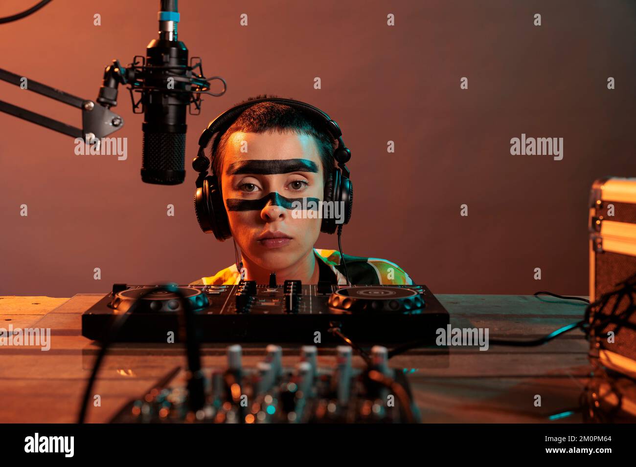 Young musician looking closely at turntables in studio, acting silly ...
