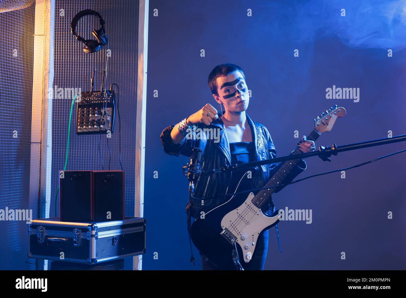 Mad crazy rocker showing clenched fist in studio with smoke, acting ...