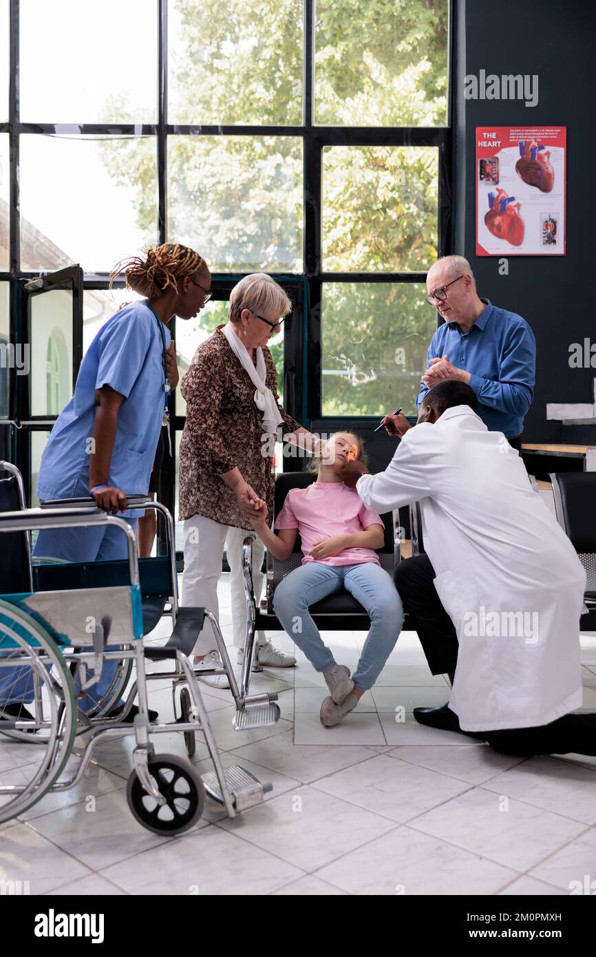 Practitioner doctor helping unconscious child after fainting on chair ...