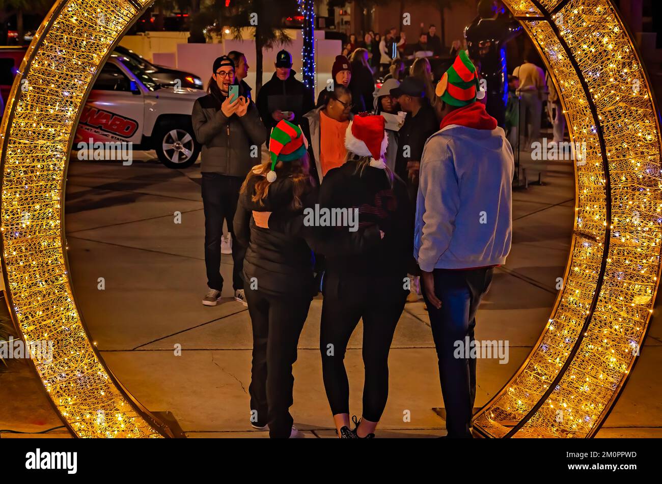 People pose for pictures beneath a lighted archway near Mardi Gras Park ...