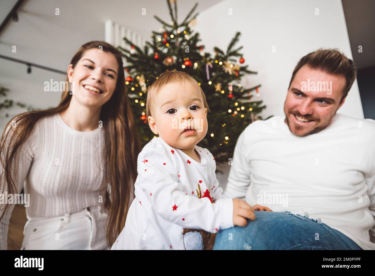 Baby girl not cooperating on Christmas photos, smiling mom and dad in ...