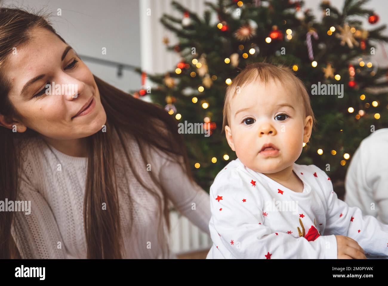 Baby girl looking in the camera while her mom watcher her, Christmas ...