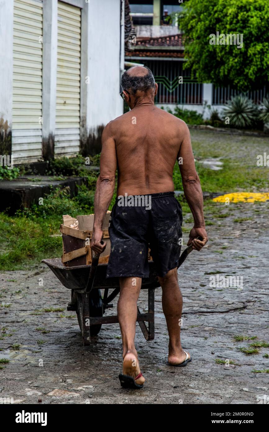 Worker man carrying goods in a wheelbarrow to the store through the ...