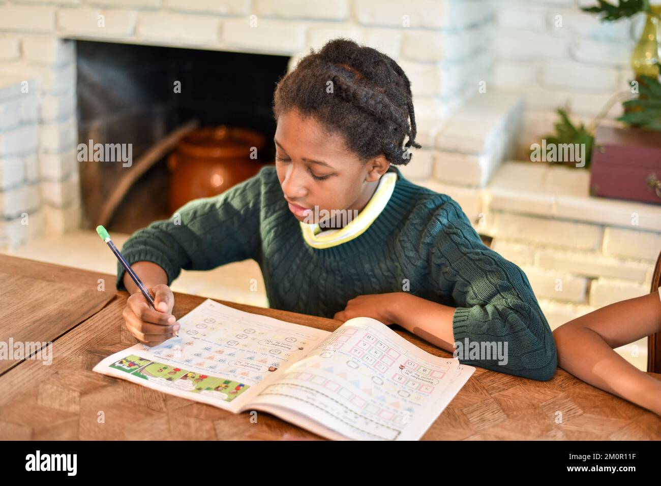 little girl doing homework at home while sitting at the kitchen table ...