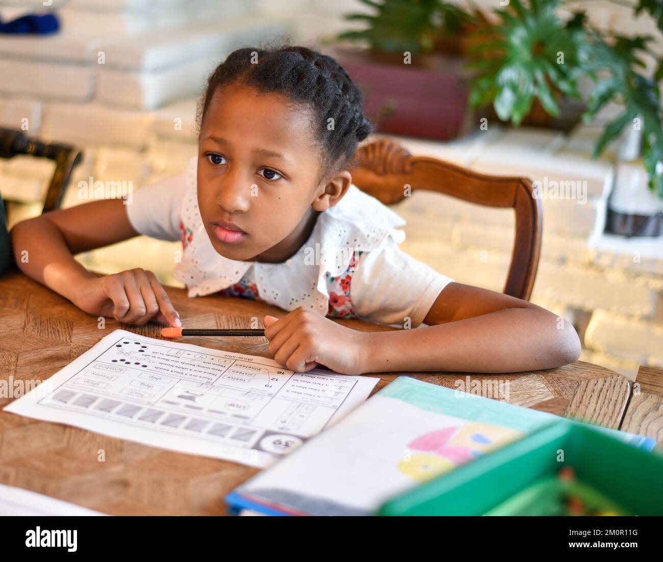 little girl doing homework at home while sitting at the kitchen table ...