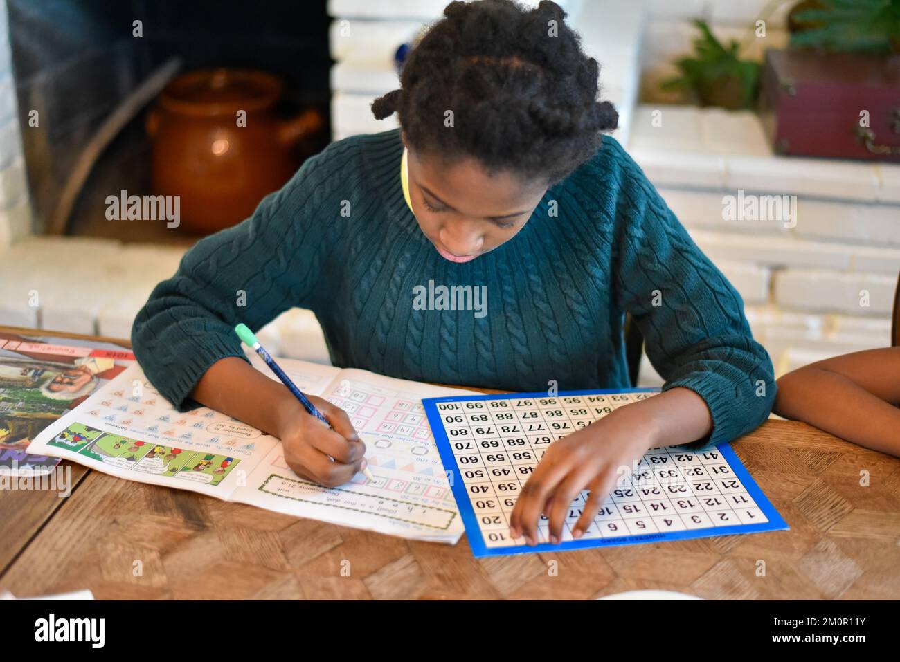 little girl doing homework at home while sitting at the kitchen table ...