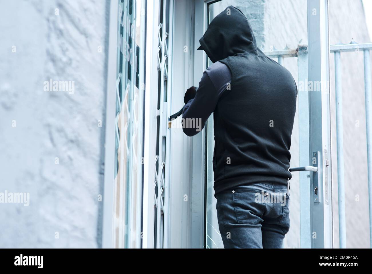 No home is safe from him. Rearview shot of a male burglar using a steel ...