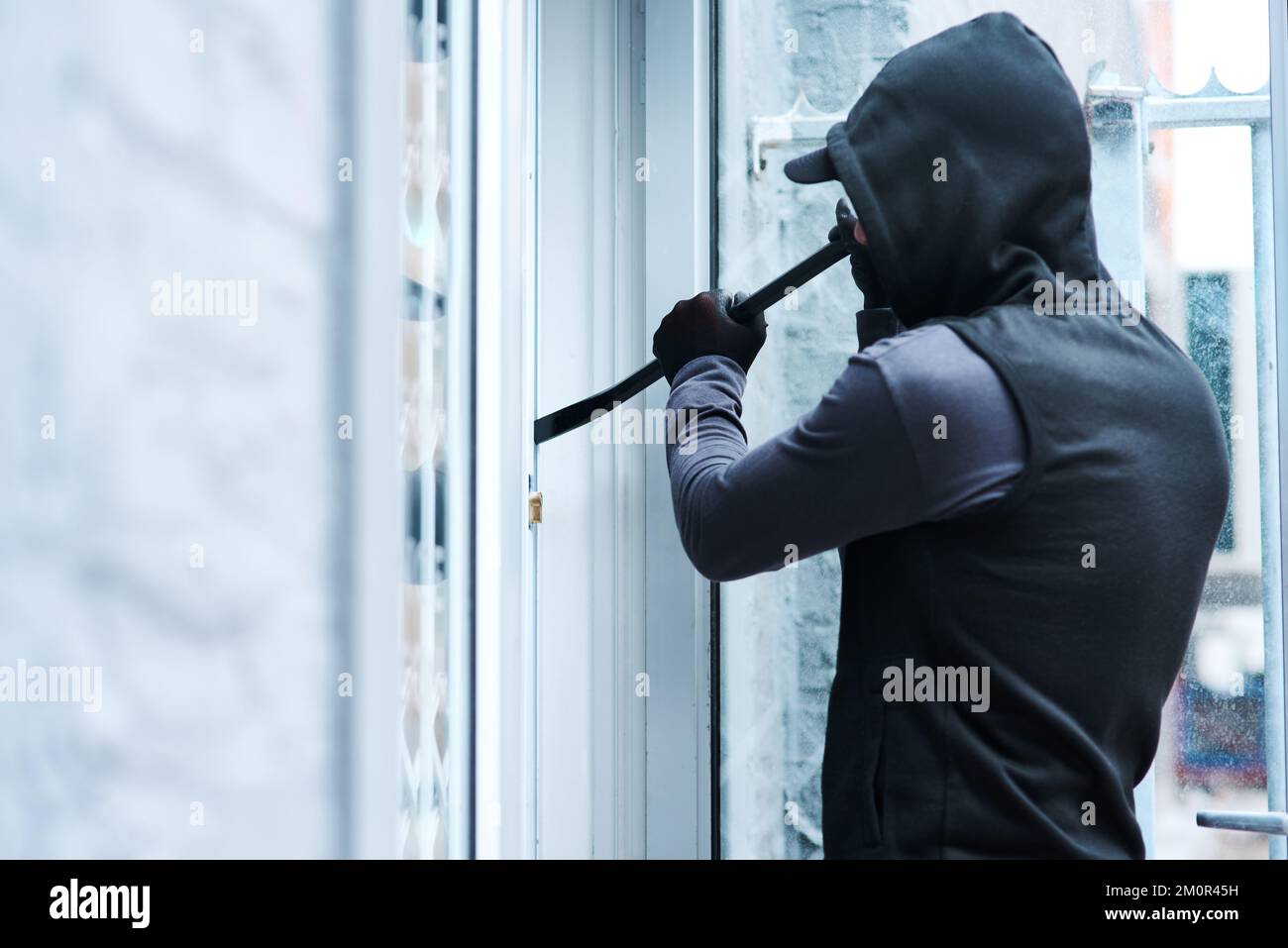 Hes forcing his way in. Rearview shot of a male burglar using a steel ...