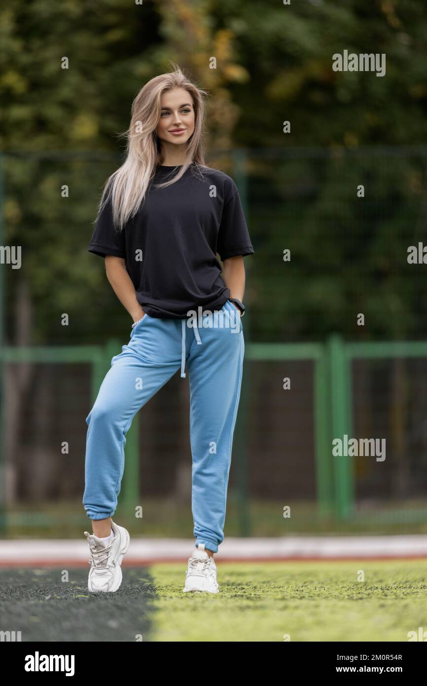 Fit blonde woman in oversized clothes posing outdoor Stock Photo - Alamy