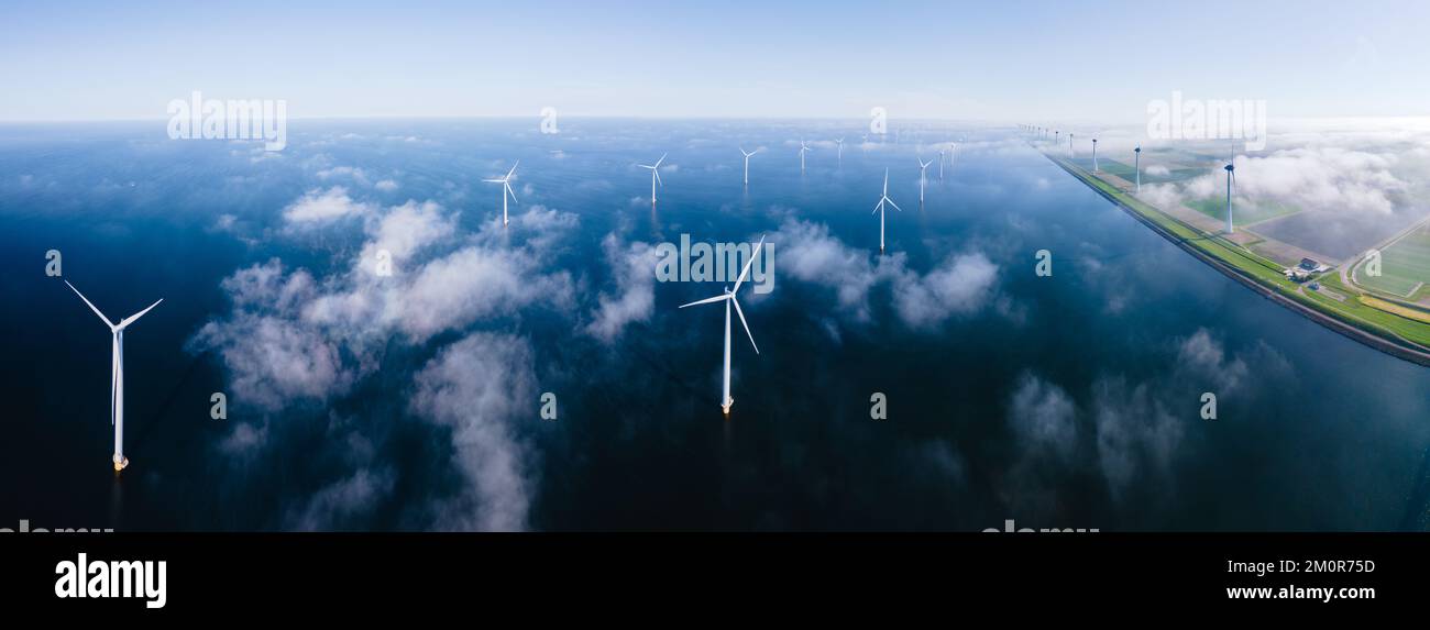 Windmill turbines at sea with a blue sky and clouds seen from a drone ...