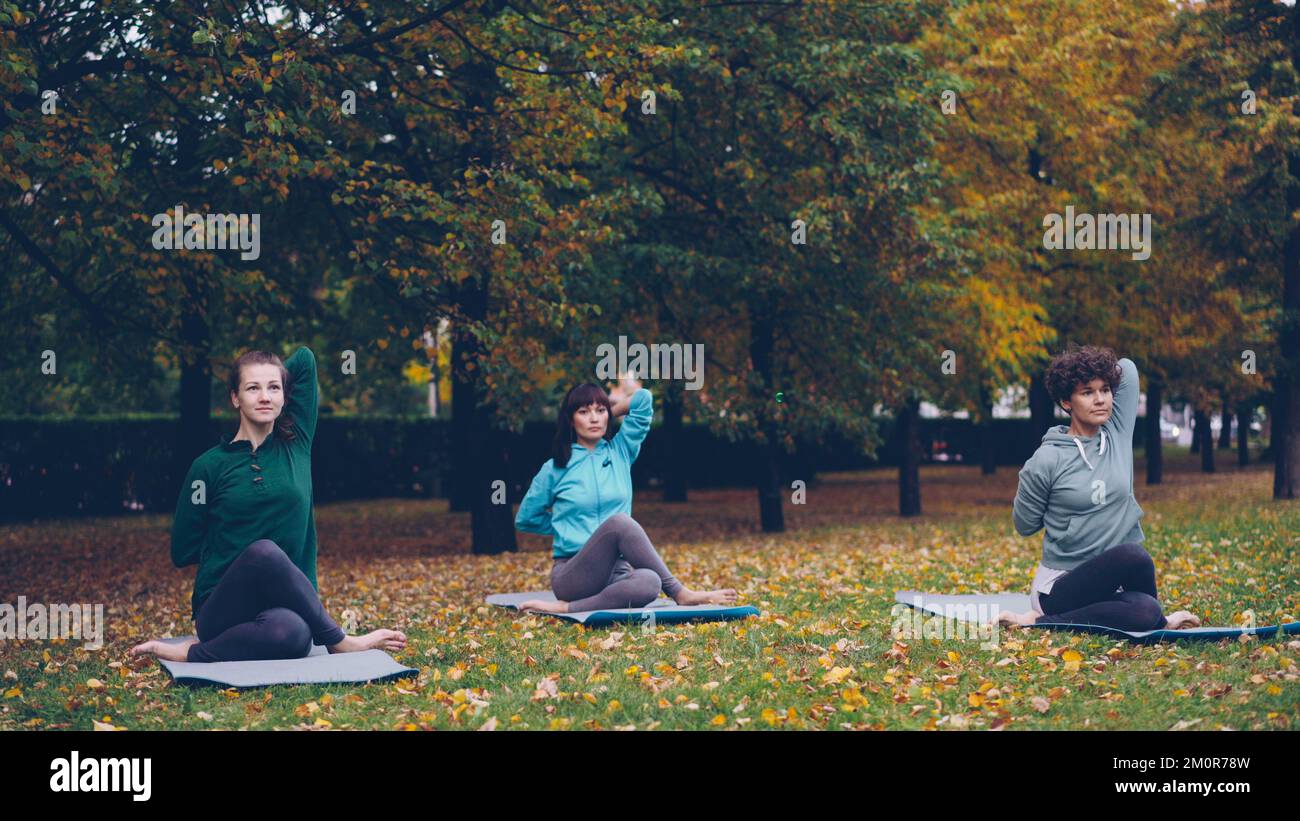 Relaxed females are sitting on yoga mats in Cow Face pose and ...