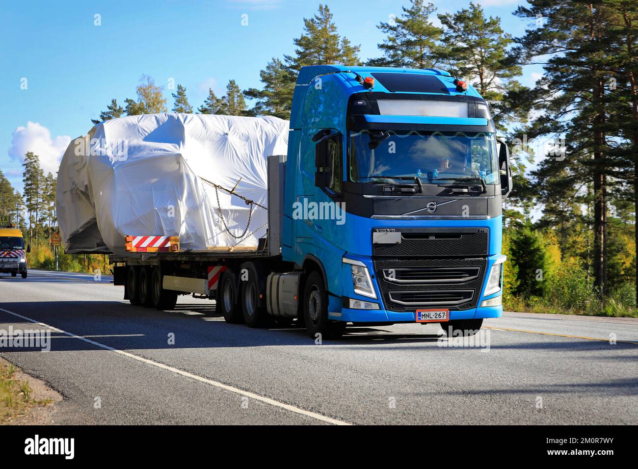 Blue Volvo FH semi truck in convoy of wide load transports towards ...