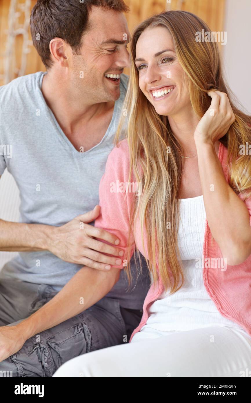 Sharing an intimate moment. A happy young couple sitting on the couch ...