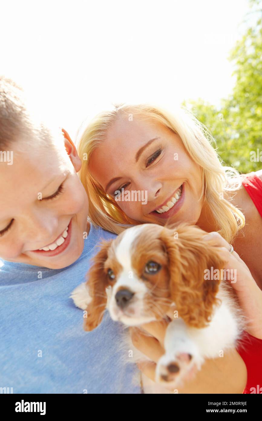 Giving their puppy love. a smiling boy with his mother holding a puppy ...