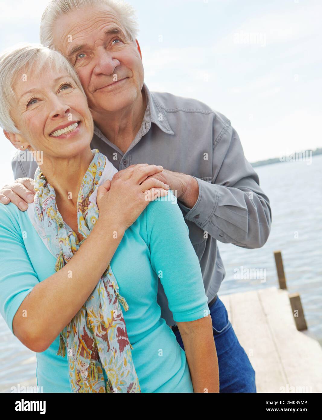 Feeling content by the lakeside. A senior couple embracing and looking ...