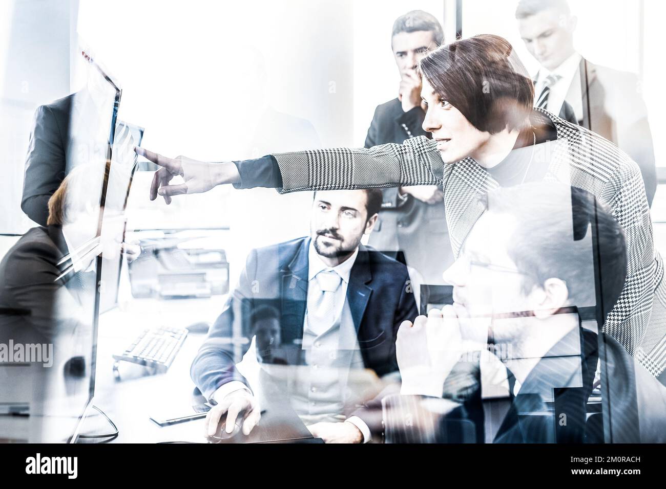 Business team looking at data on multiple computer screens in corporate ...