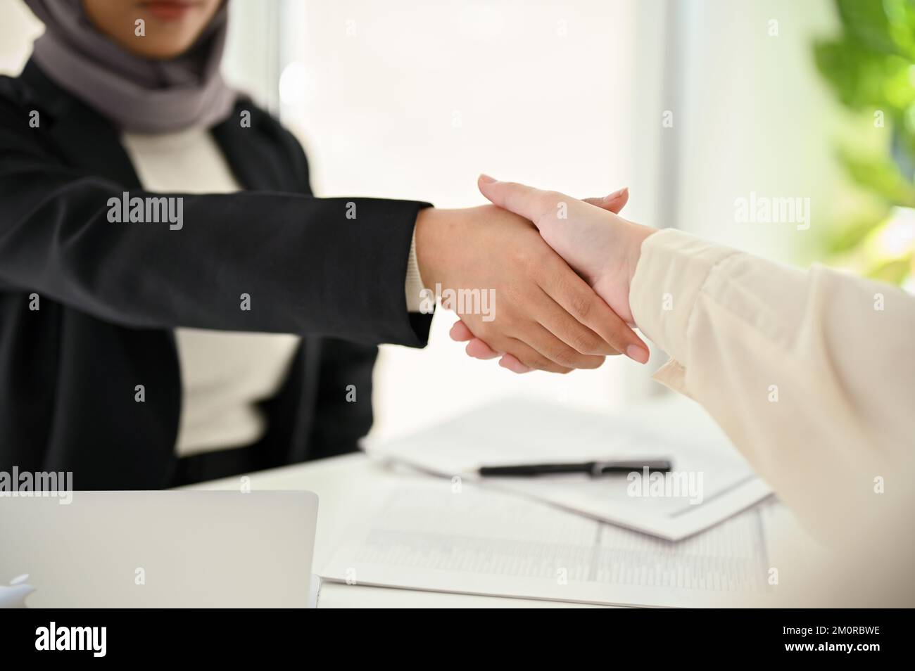 Close-up shot of a professional Muslim businesswoman shaking hands with ...