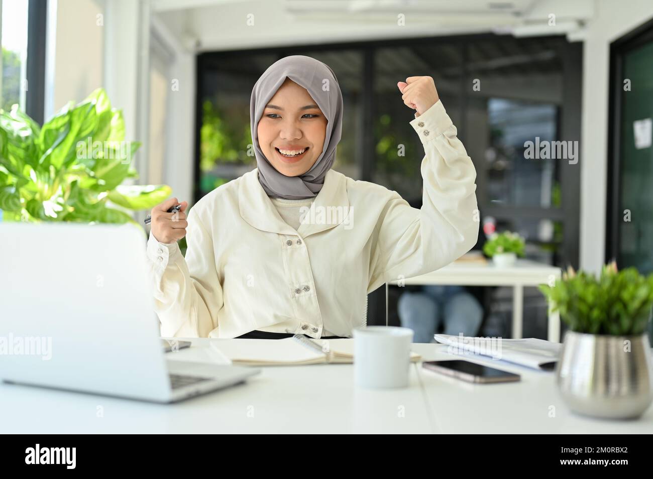 Happy and joyful young Asian Muslim female office worker hands up ...