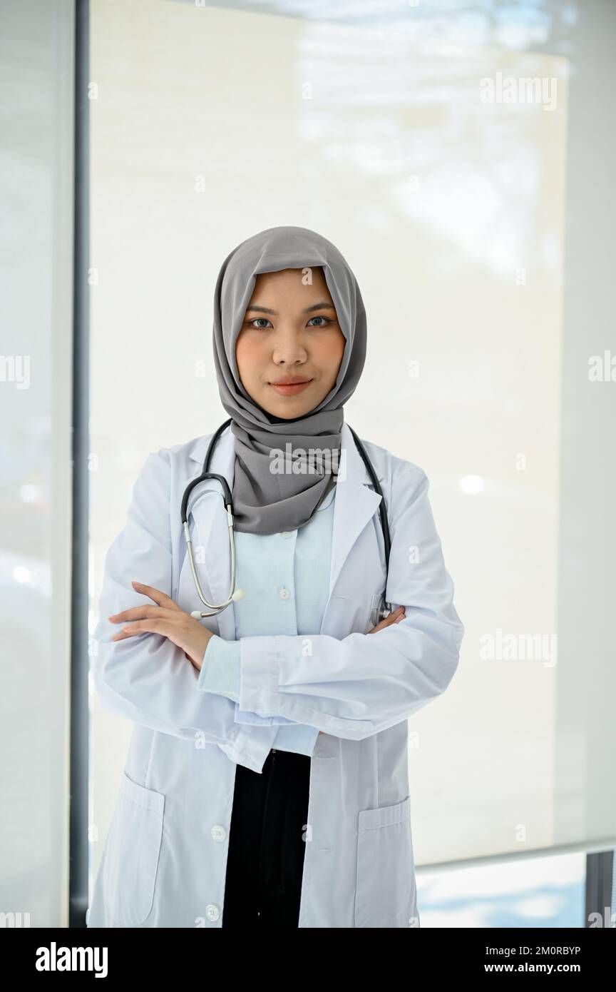 Portrait, Professional Muslim female doctor in uniform and hijab stands ...