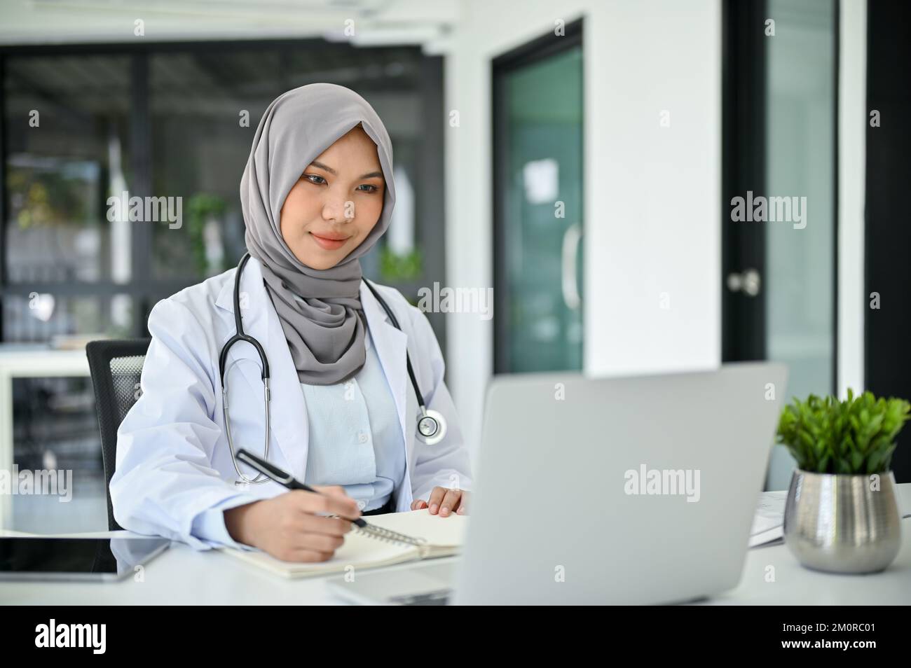 Beautiful and professional Muslim female doctor in hijab focusing on ...