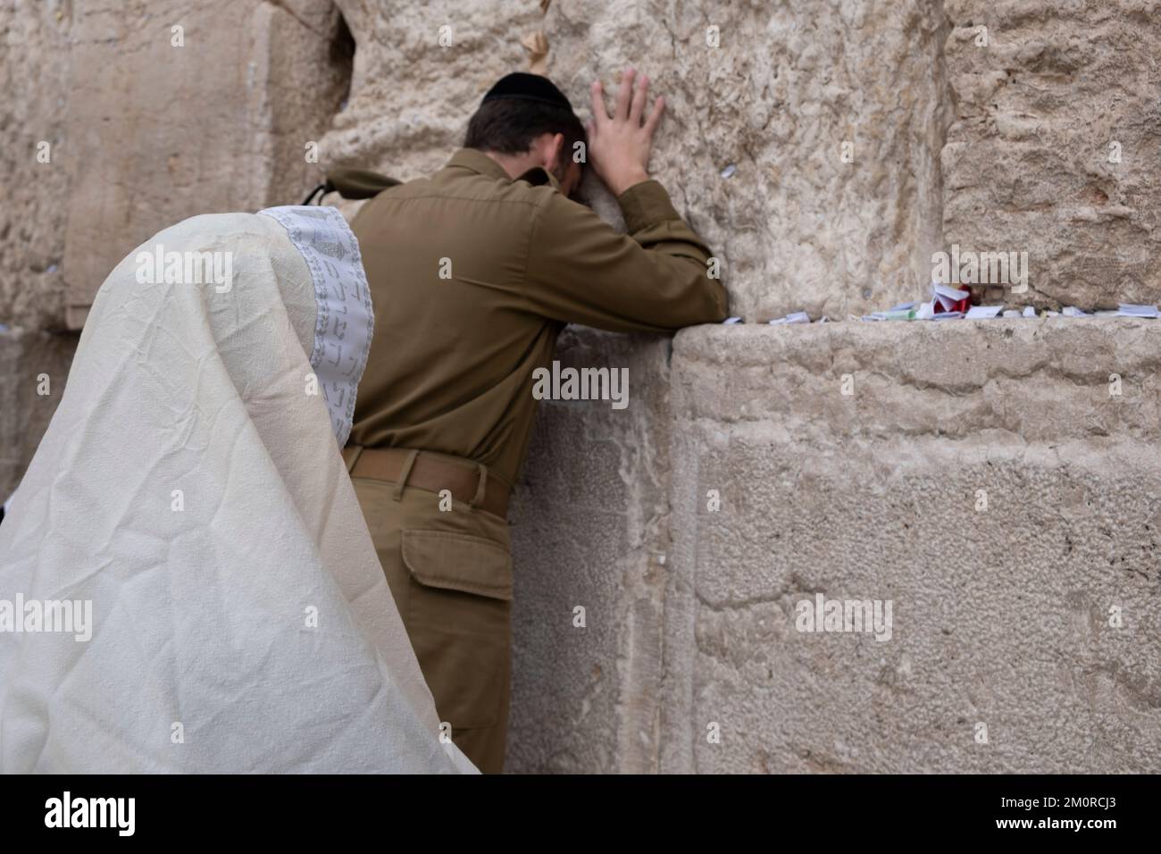 An Israeli soldier prays next to a religious Jew wrapped with ...
