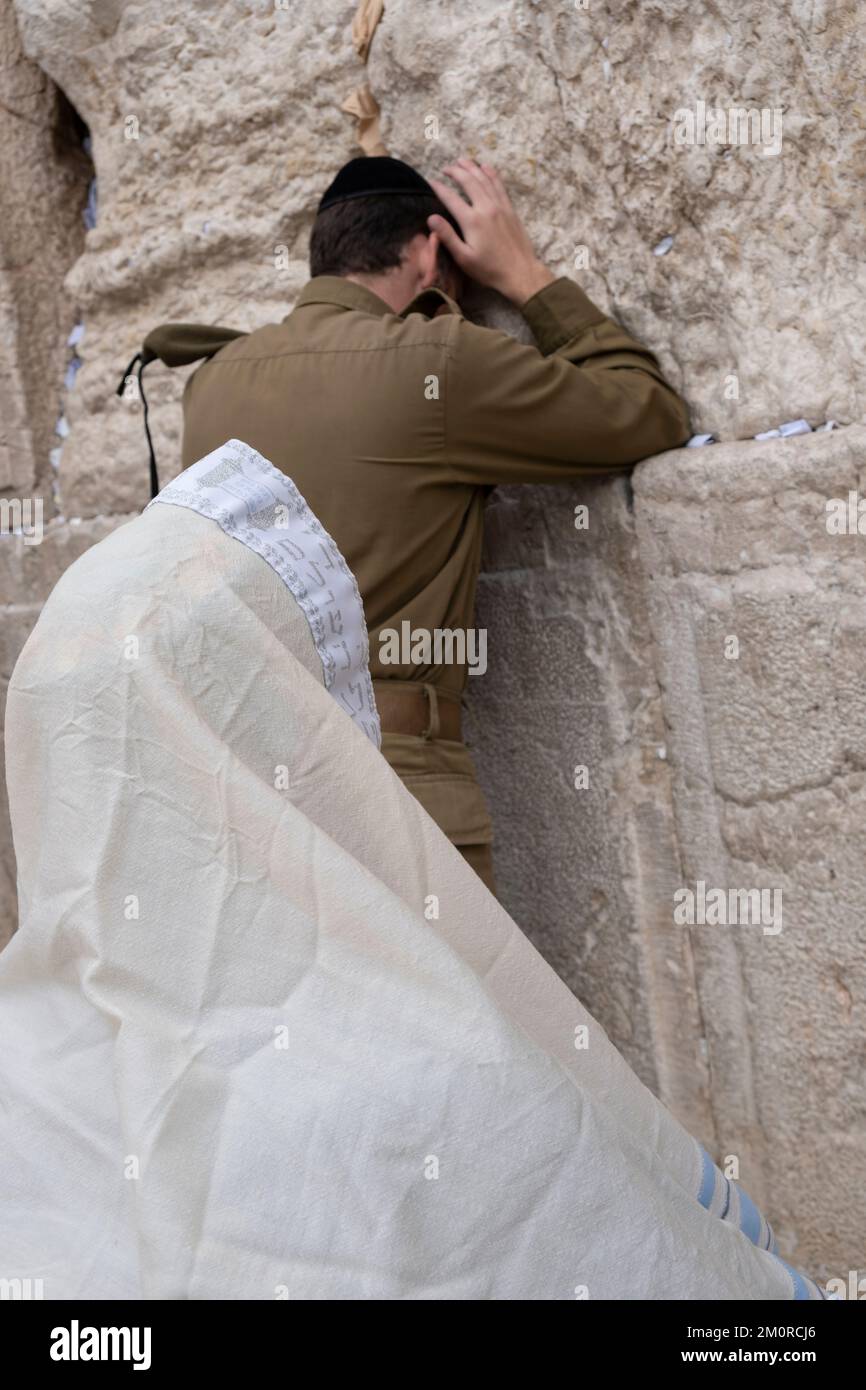 An Israeli soldier prays next to a religious Jew wrapped with ...