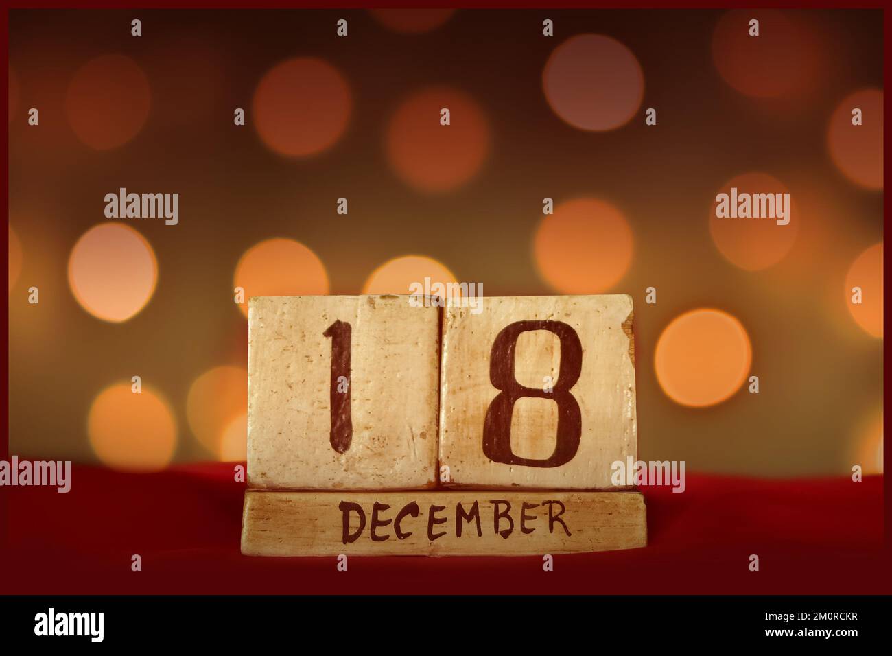 December 18 vintage wooden block calendar on red fabric, festive bokeh ...
