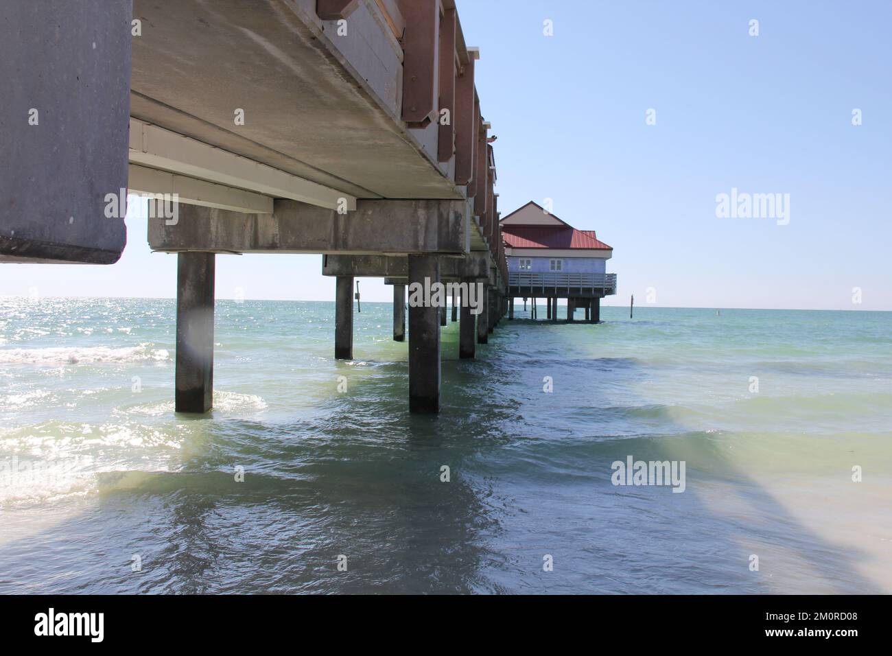 A scenic view of a pier on tranquil waves of a turquoise sea on a sunny ...