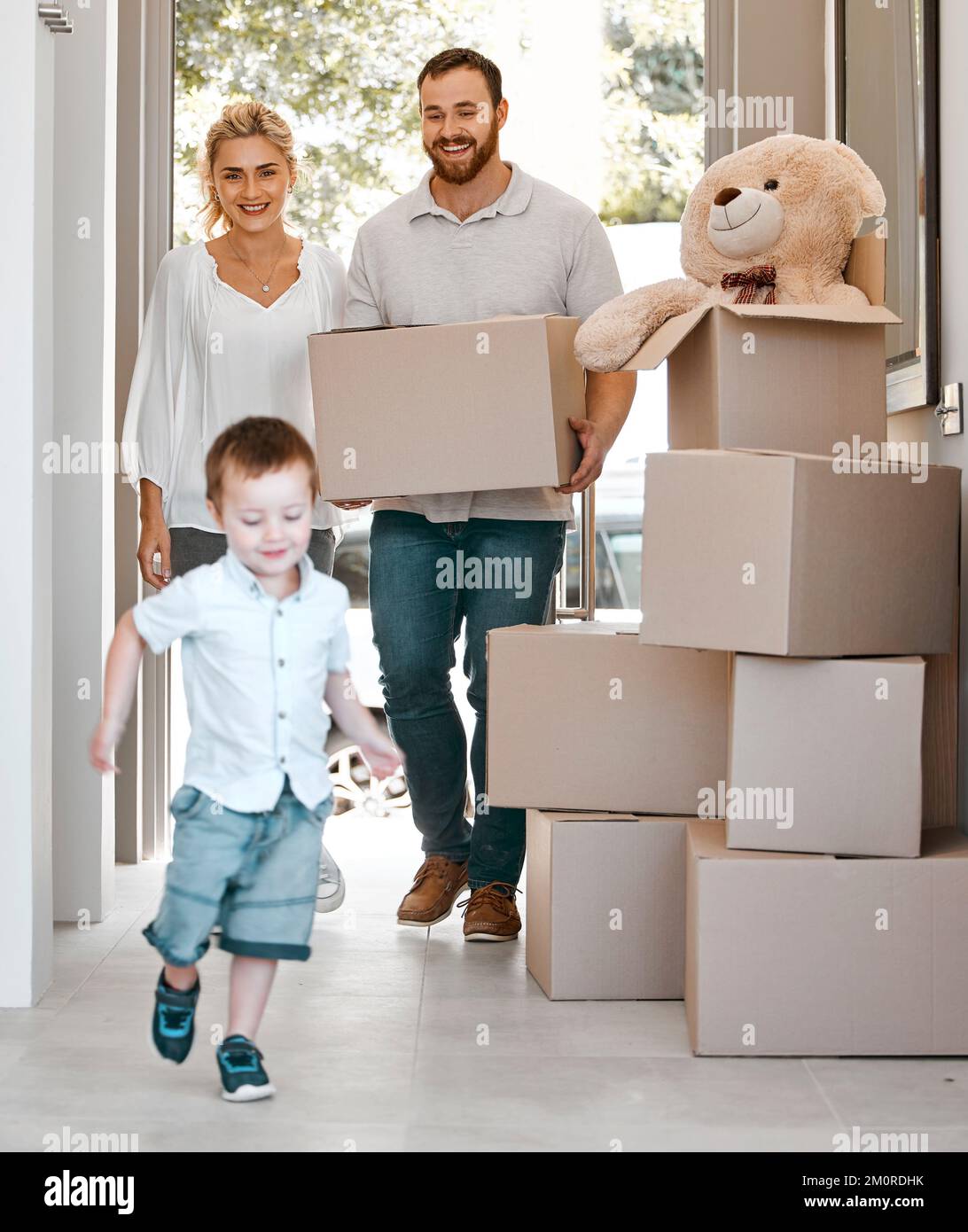 Excited little boy running into his new home. Happy family moving into ...