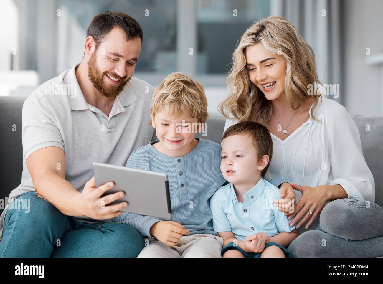 Happy relaxed family of four using a digital tablet device while ...