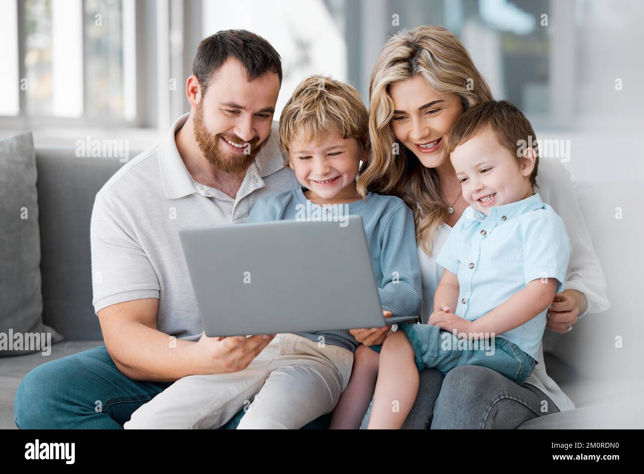 A happy family using a laptop on the sofa with children at home ...