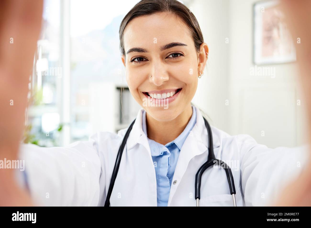 Portrait of a young mixed race female doctor taking a selfie while ...