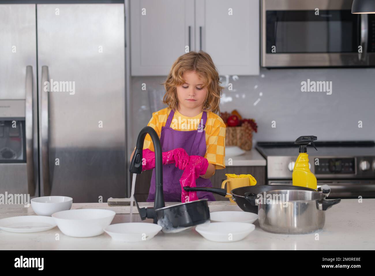 Cleaning house. Child doing and wiping dishes in kitchen. Little kid ...
