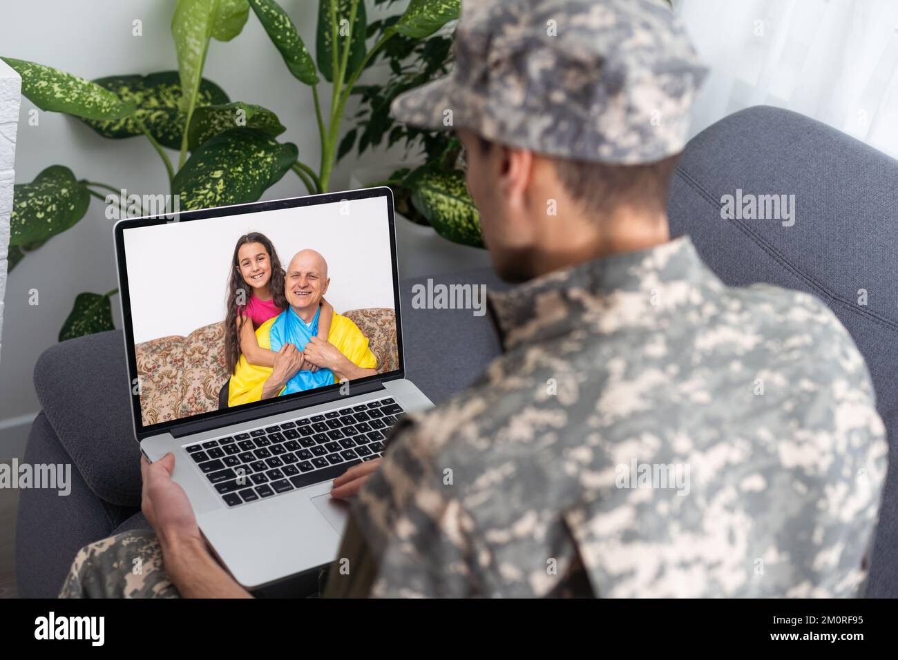 Young soldier in military uniform talking to someone while having video ...
