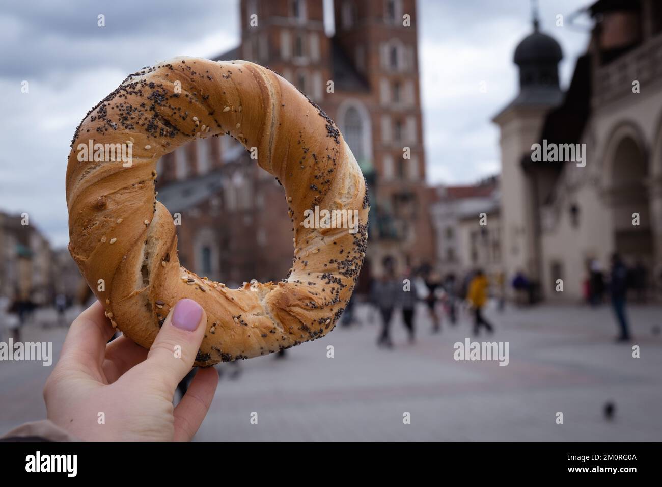 Tourist woman eating bagel obwarzanek traditional polish cuisine snack ...