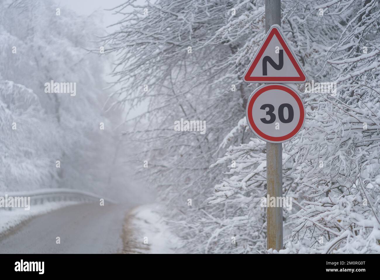 Snowy driveway and road sign speed limit 30 km. Winter forest after ...