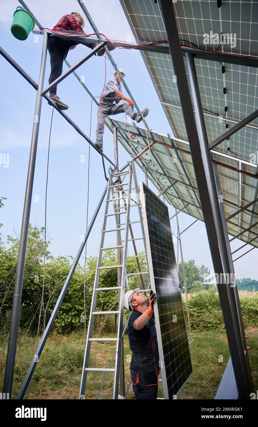 Workers mounting photovoltaic solar panel system outdoors. Men ...