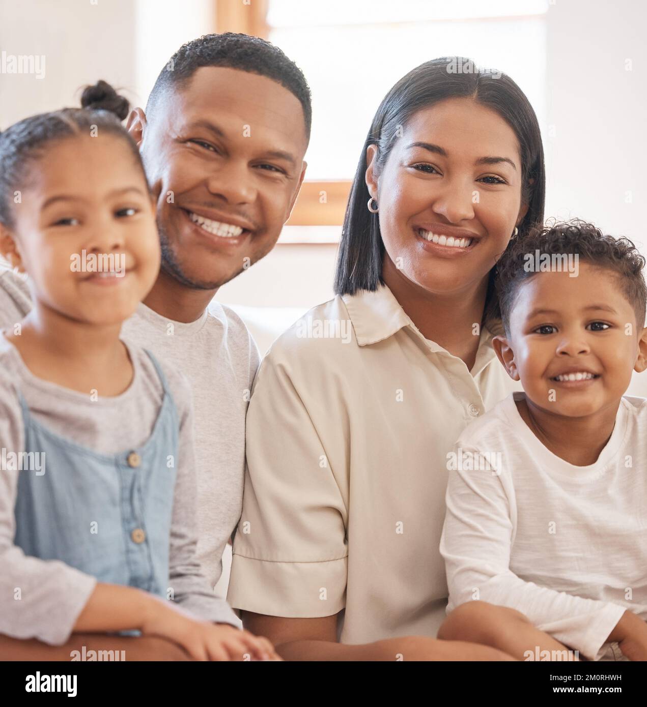 Portrait of smiling mixed race family relaxing together at home ...