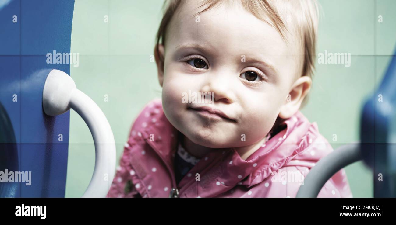 Cute baby girl having fun on a playground and looking at the camera ...