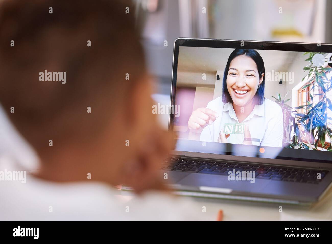 Little girl on a video call with her teacher using a laptop. Young female teacher doing a ...
